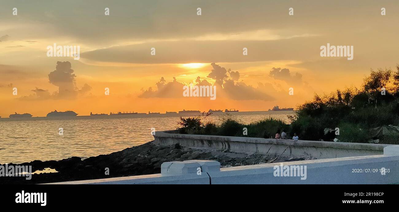 Group of people gathered together on a beach, facing the horizon and ...