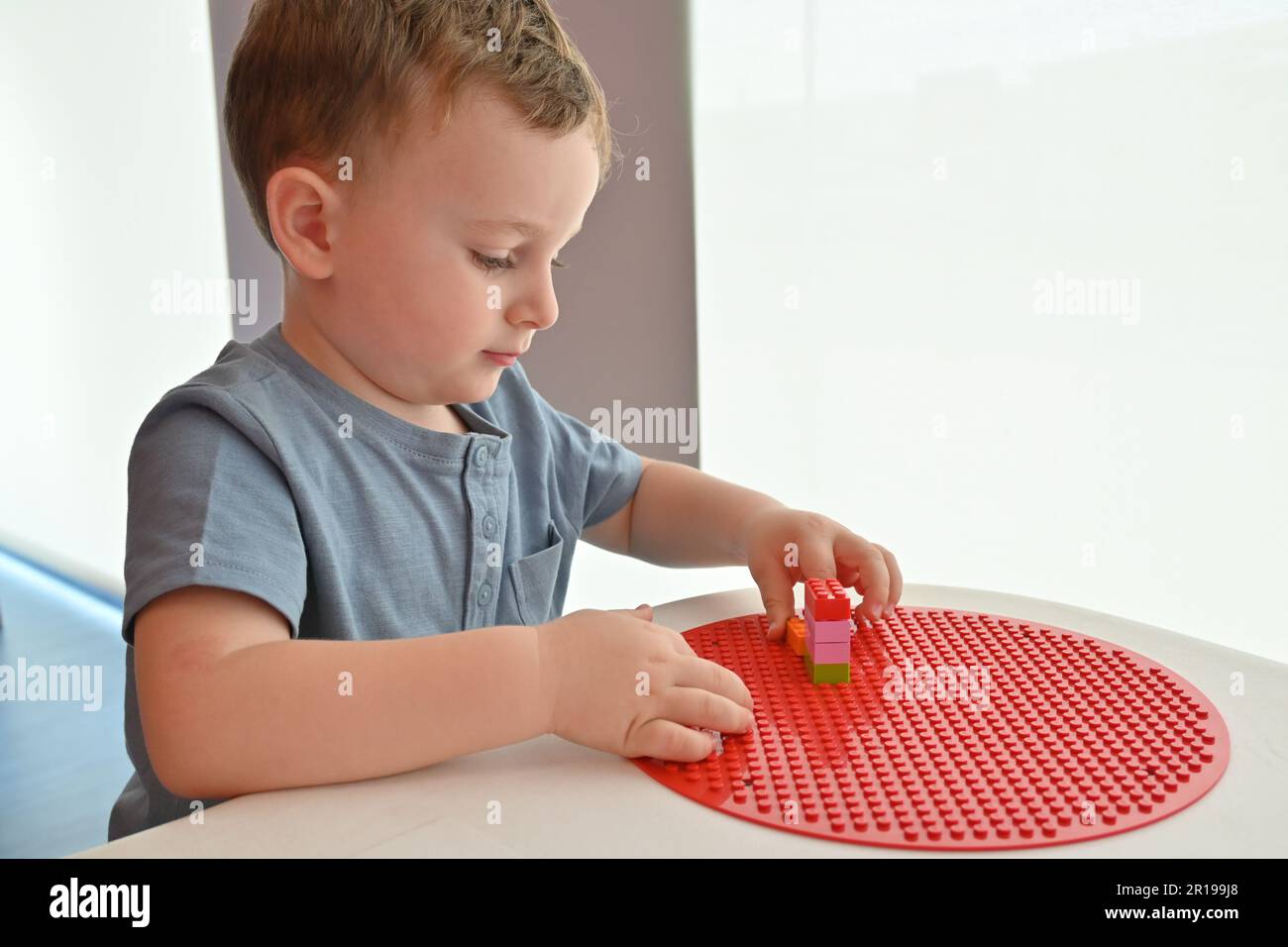 Little child playing with lots of colorful plastic toys indoor ...