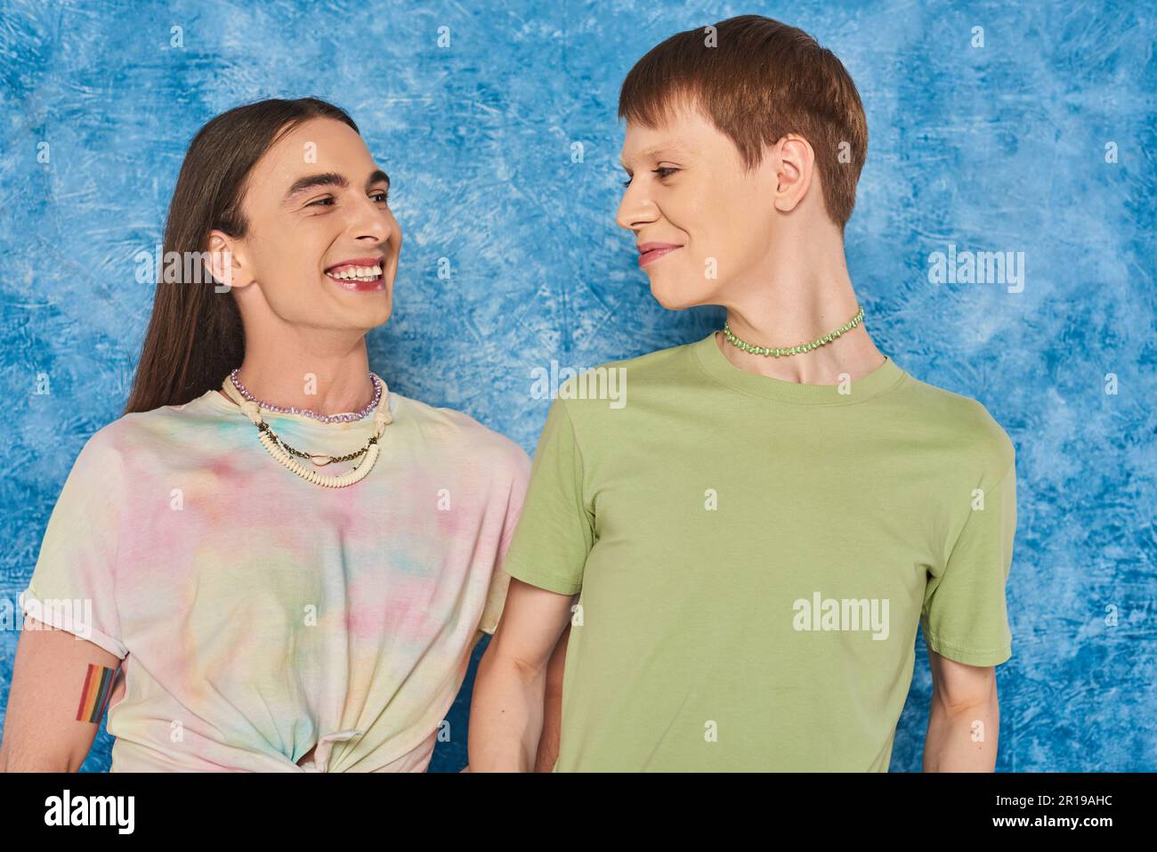 Portrait of cheerful queer friends in casual clothes looking at each ...