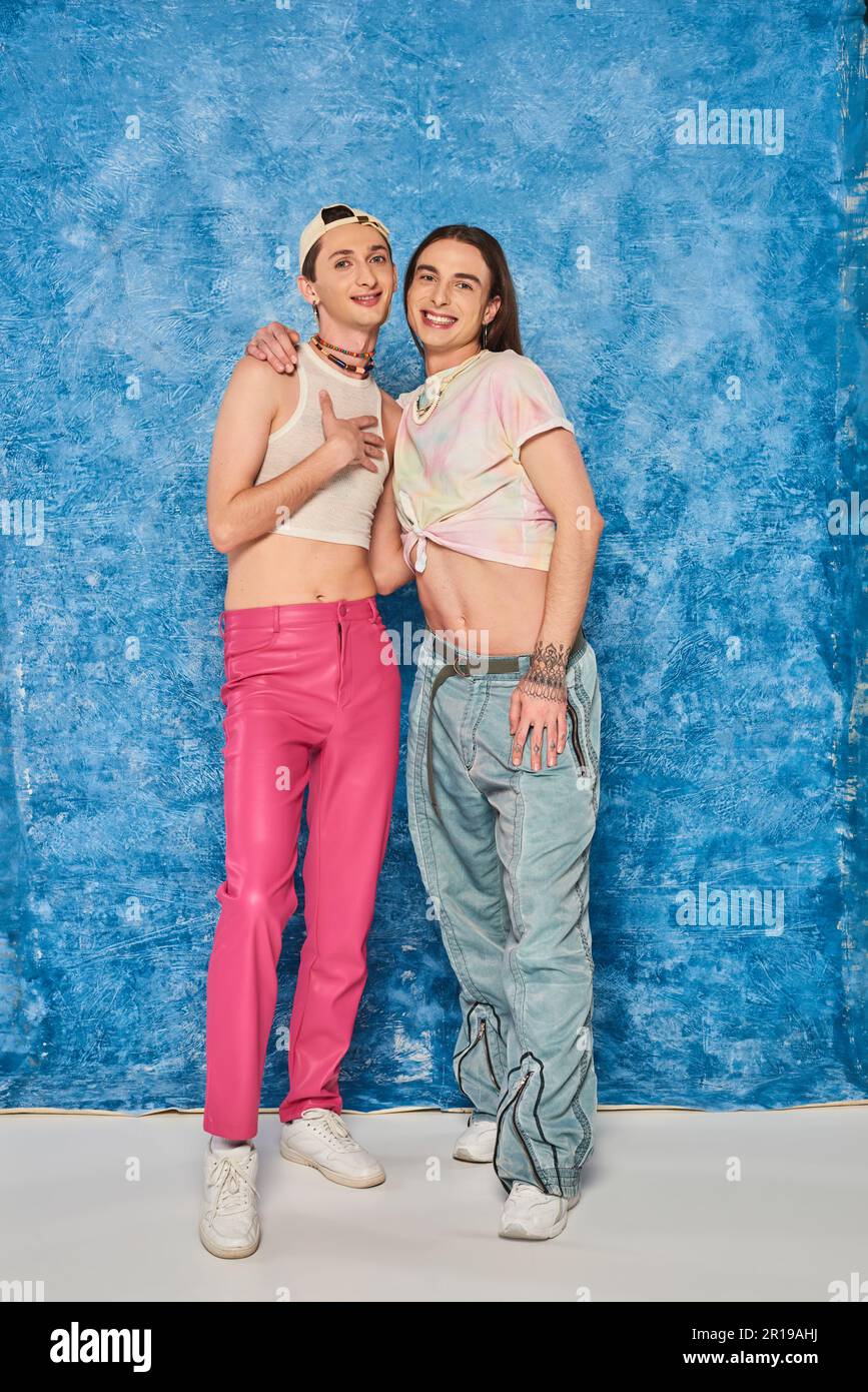 Full length of positive gay friends in stylish outfits hugging and ...