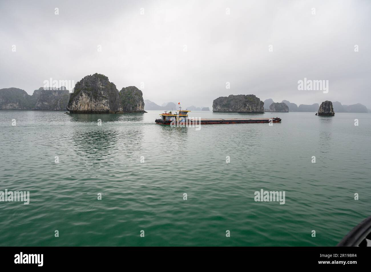 A barge sails past the typical limestone islands in Bai Tu Long Bay ...