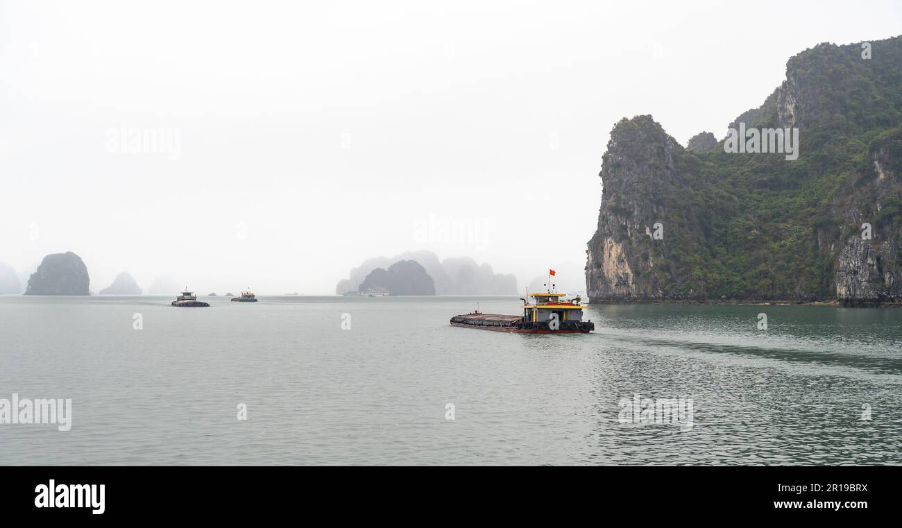 Barges and boats sailing among the characteristic limestone islands and ...