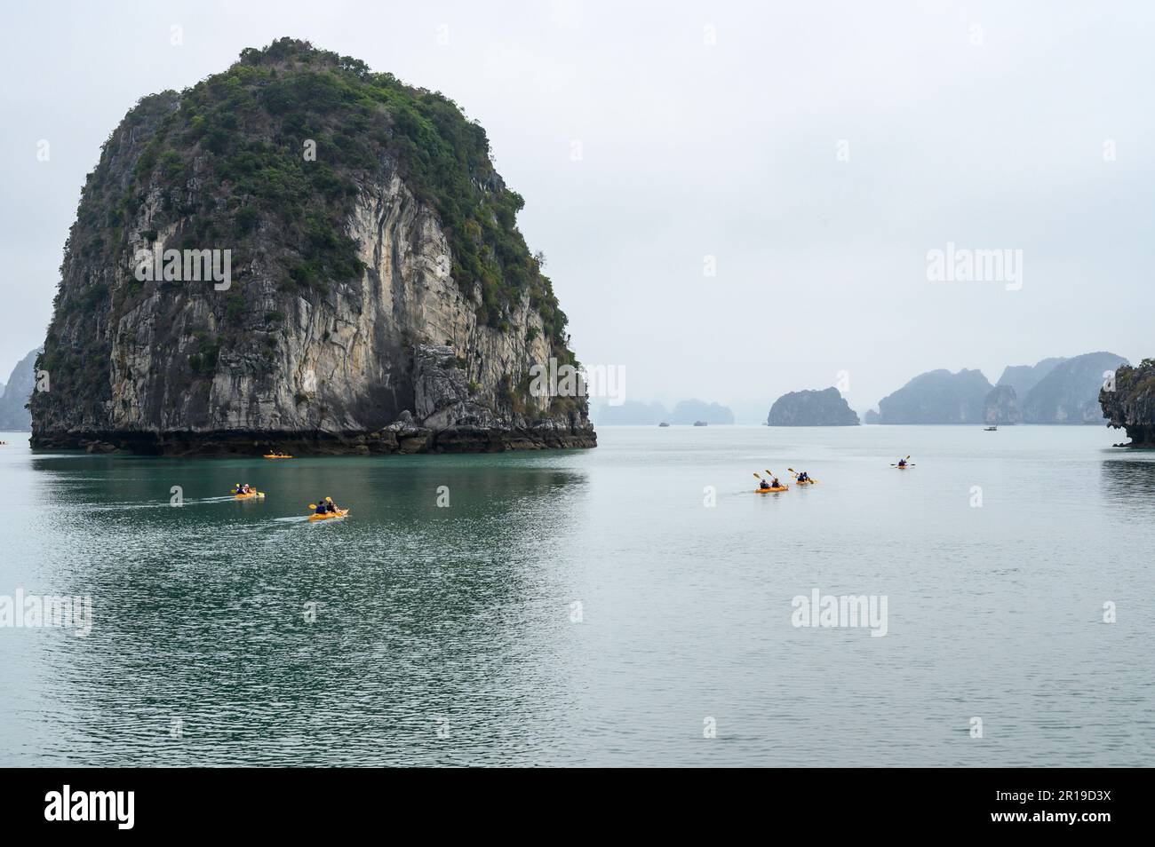 Tourists in kayaks paddling on the water among the typical limestone ...