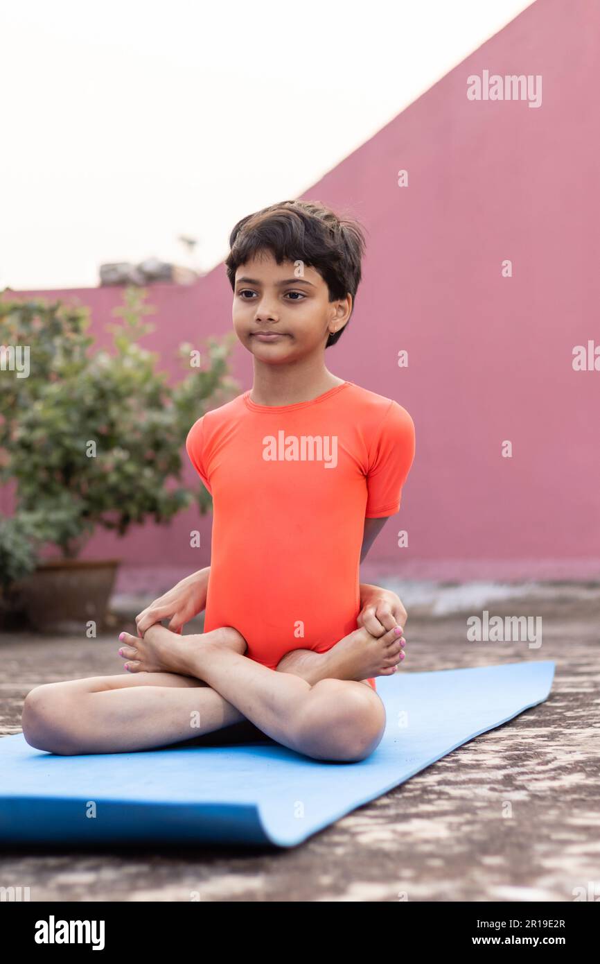 An Indian girl child practicing Baddha Padmasana yoga on yoga mat ...