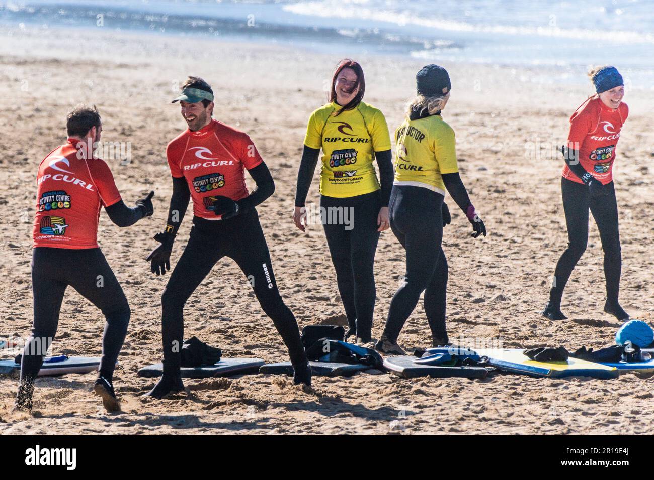 People playing a game to warm up during a surfing lesson on Fistral ...