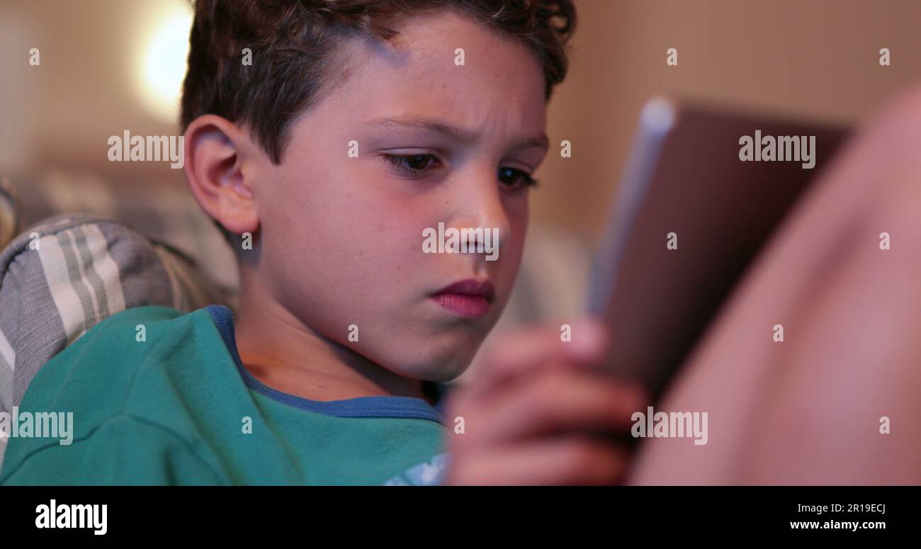 Young boy child using tablet device technology. Kid staring at screen ...