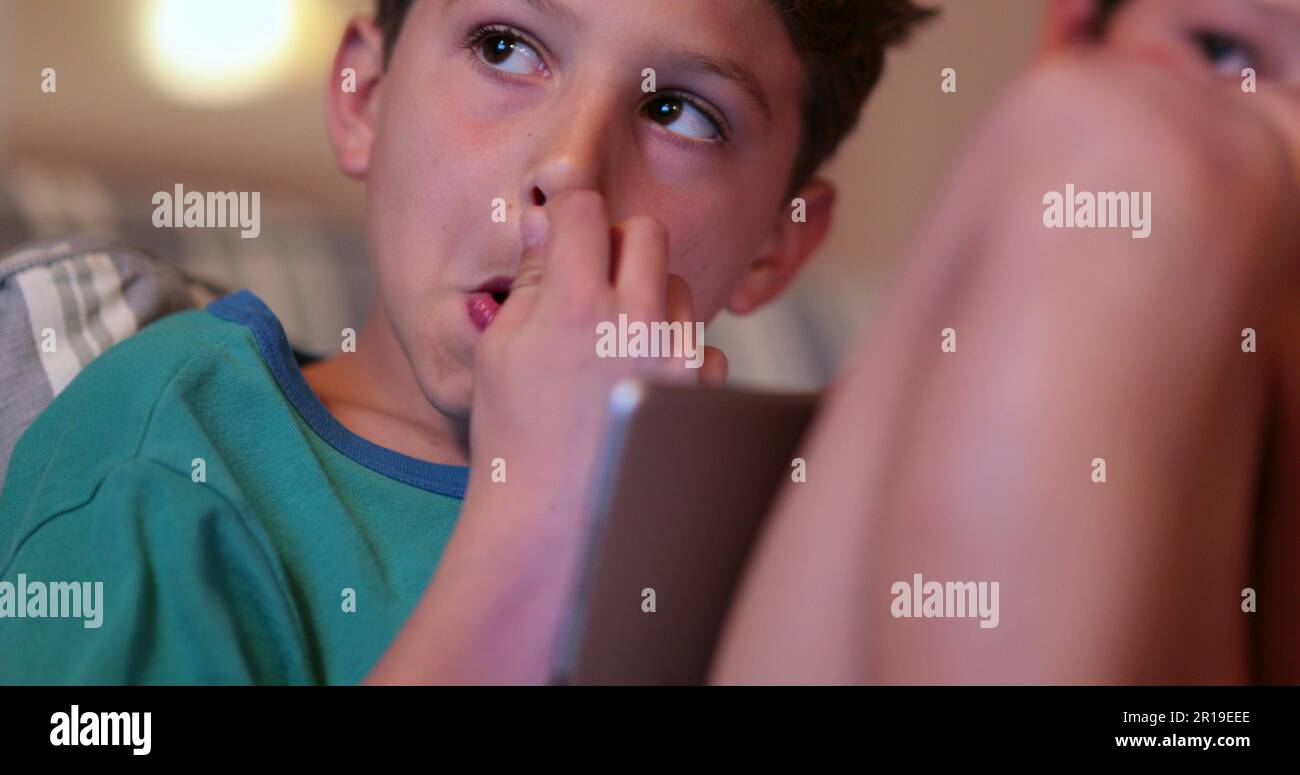 Young boy scratching face while using tablet device at night Stock ...