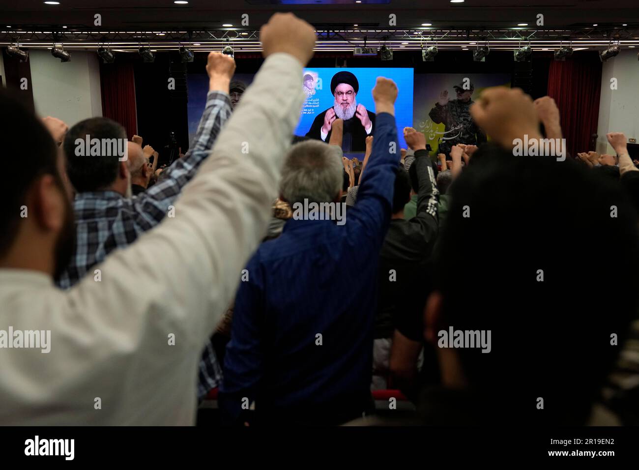 Supporters of the Iranian-backed Hezbollah group raise their fists and ...