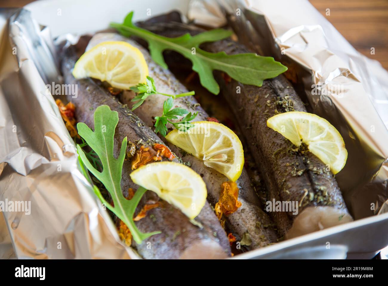 Raw fish with seasonings and spices prepared for baking in foil, in a ...
