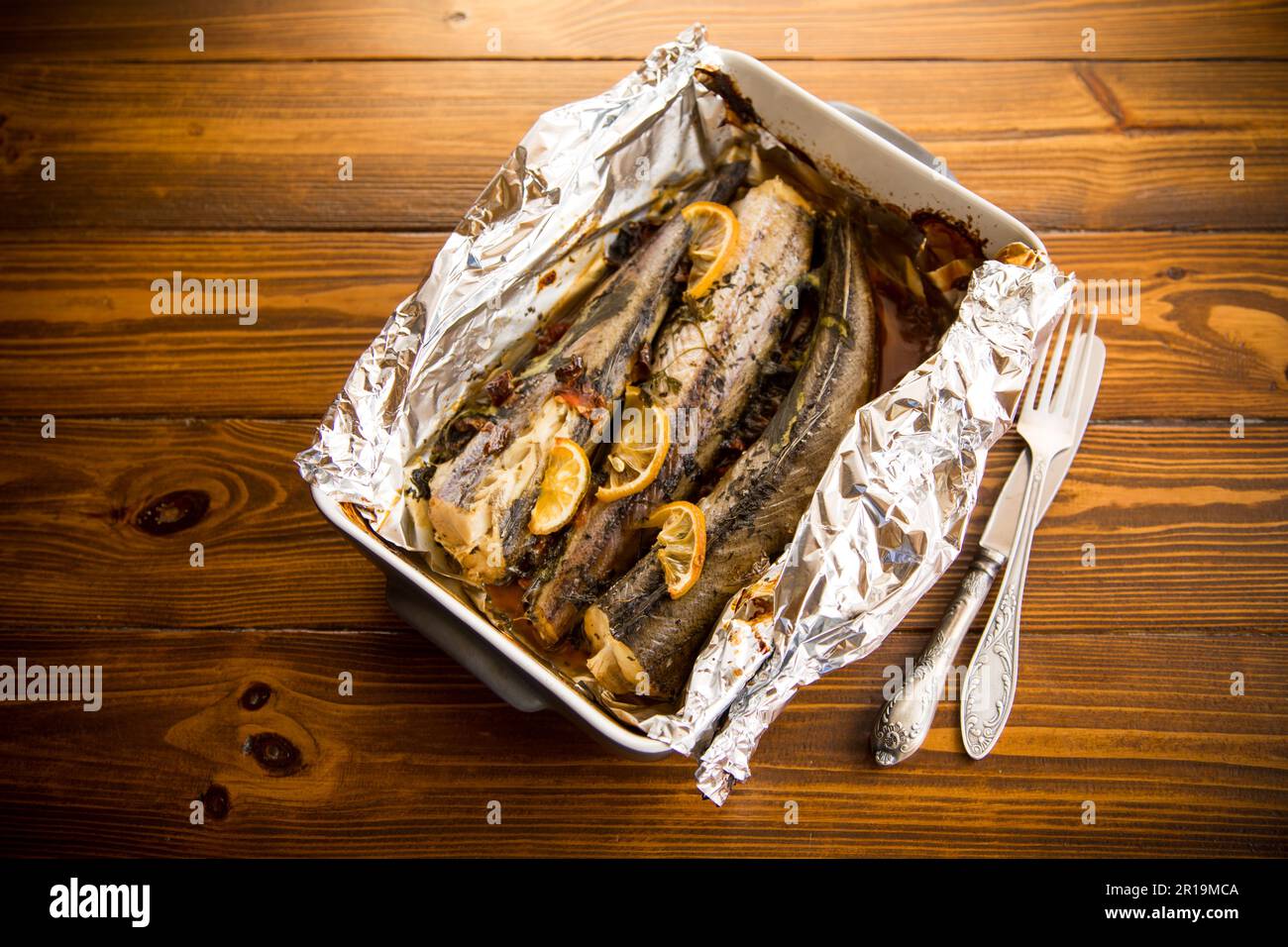 Baked fish with seasonings and spices in foil, in a ceramic form Stock ...