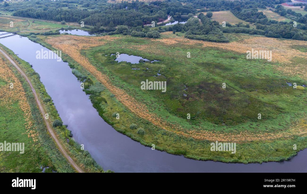 An aerial view of a river and a green field with lush trees. Romo ...