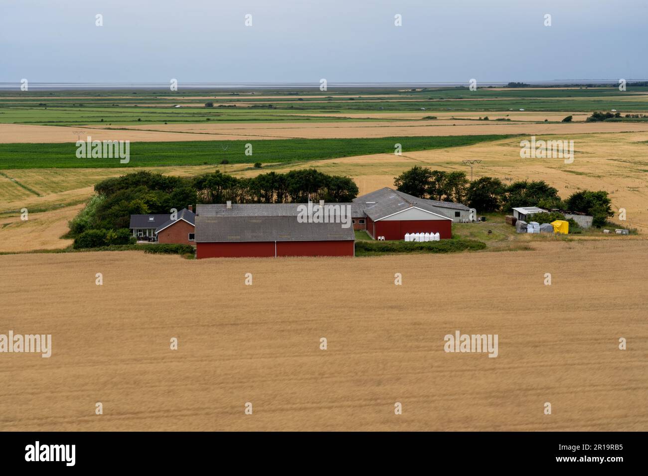 A rural landscape with a large, vibrant red barn set in the middle of a ...