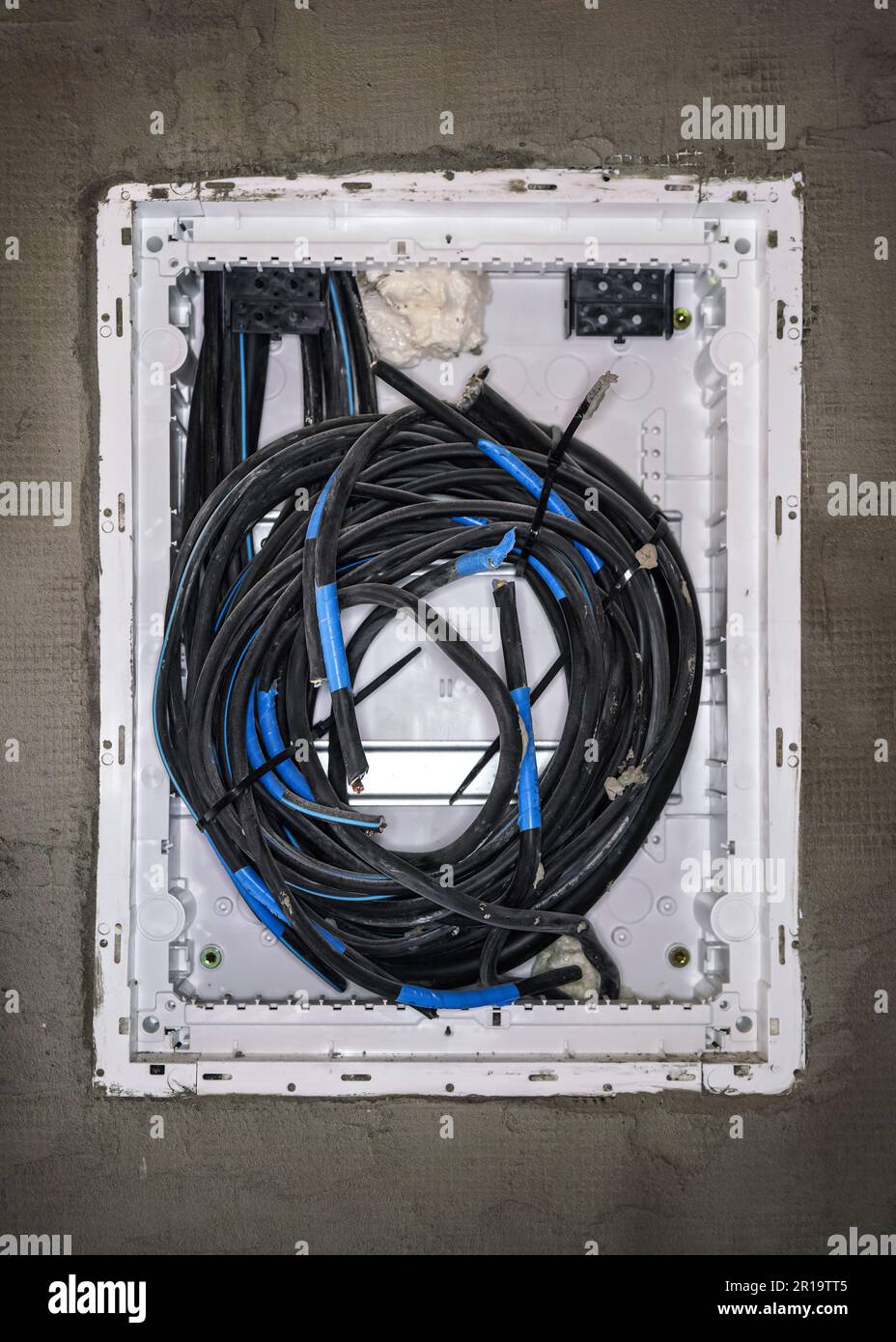 White plastic cables box with black wires installed on new gray wall at ...