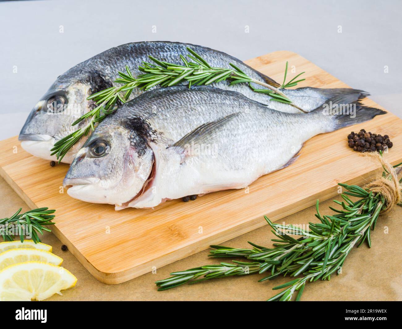 Raw fish with ingredients as lemon, peppers and rosemary for cooking on ...