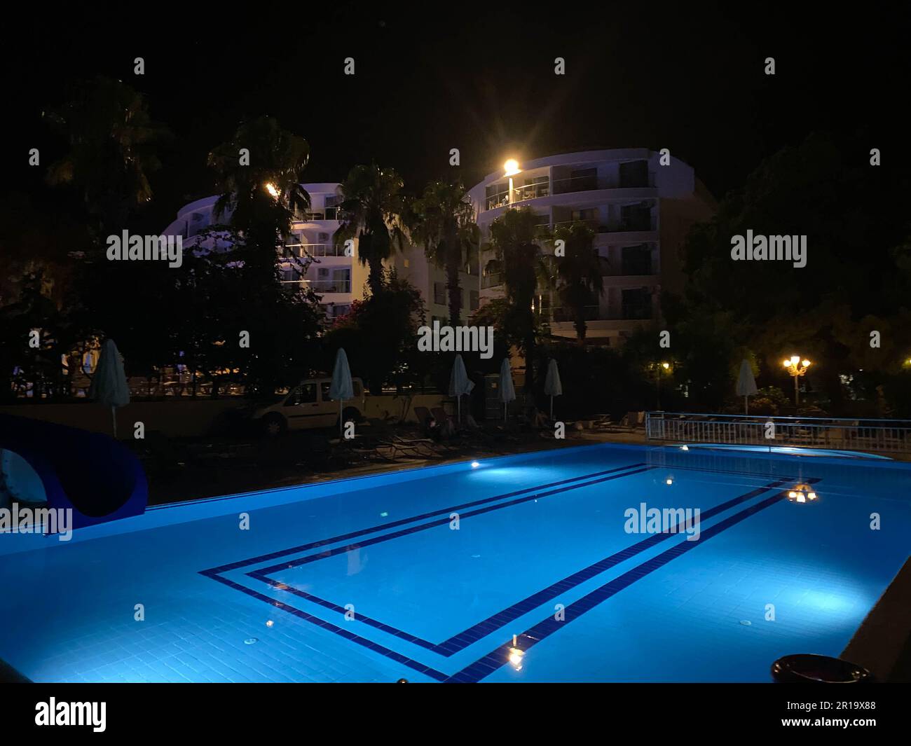 Swimming pool and a grass beach umbrellas with lounges at night, dawn ...