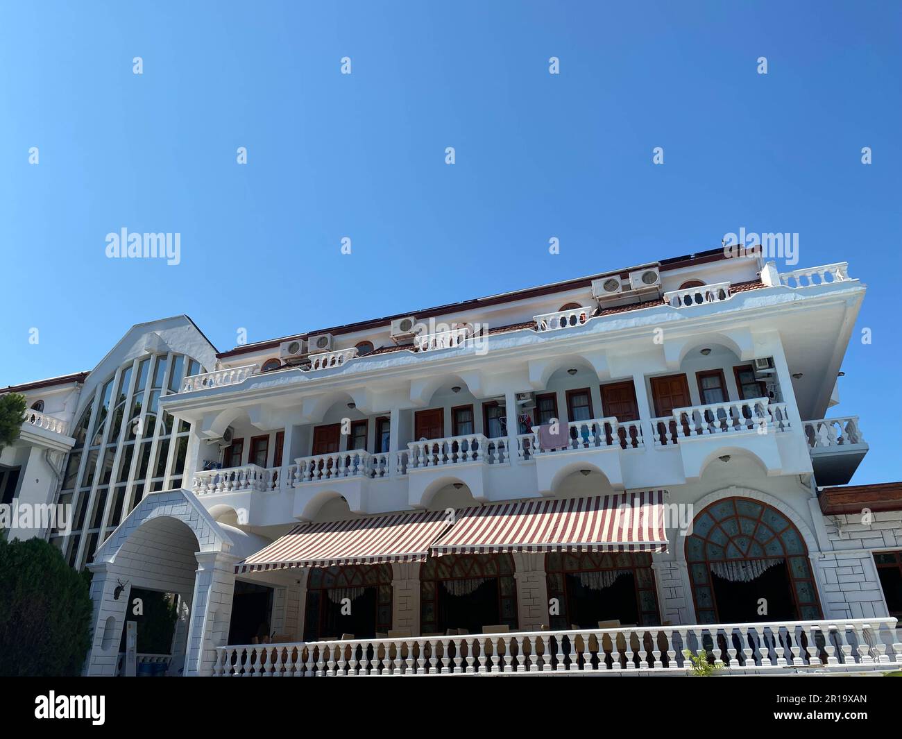 fragment of a facade of a building with balcony with table and chair ...