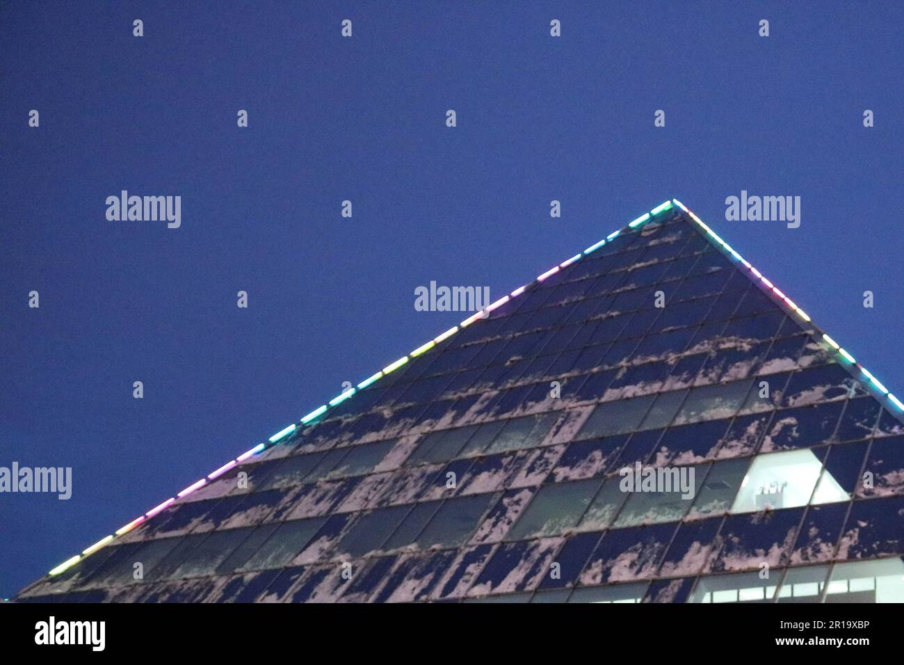 The corner of a triangular, glass, office, modern building with ...