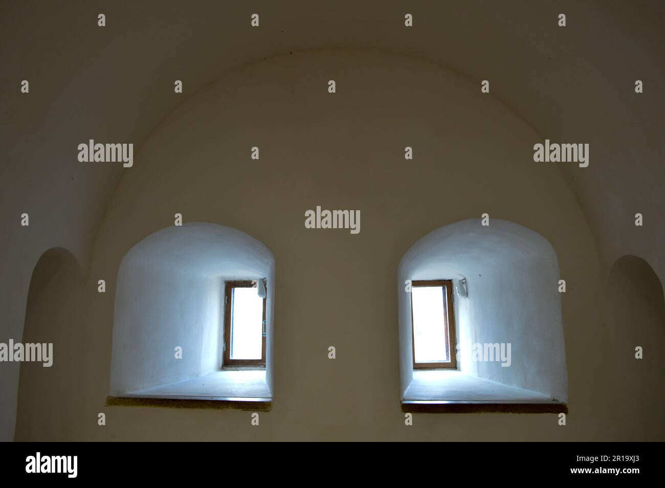Small narrow windows with an arch on an old ancient stone thick wall in ...