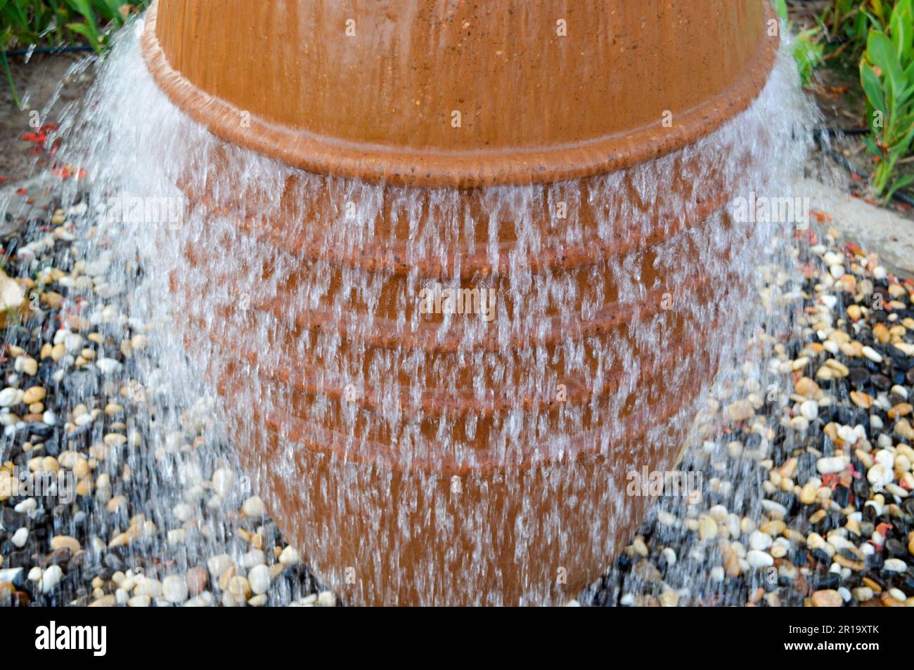 A beautiful little fountain in the form of a brown vase, a jug with ...