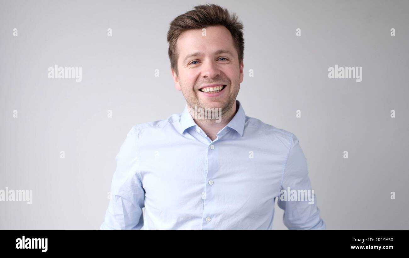 The young European man confidently looks into the camera and smiles ...