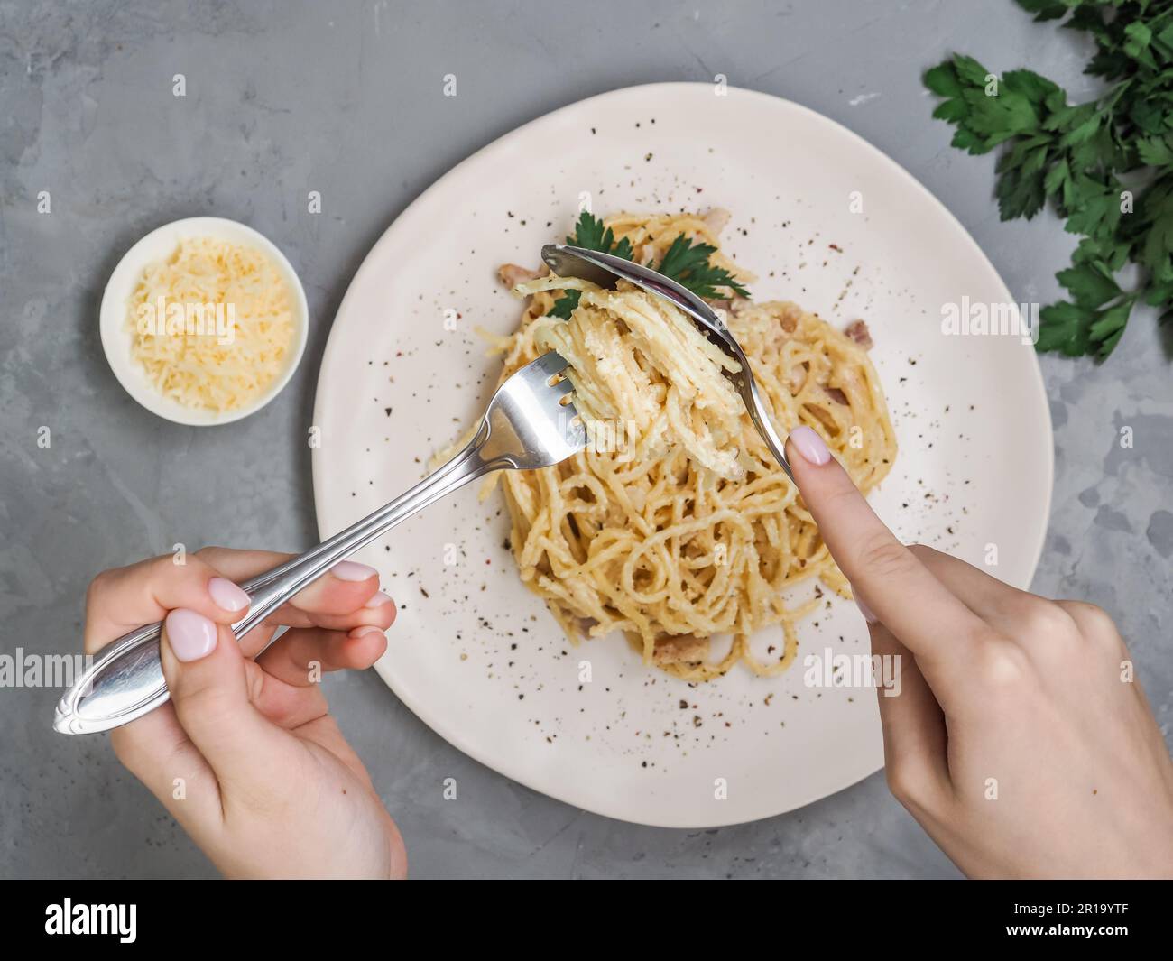 Women eating a plate of homemade carbonara with parsley, crisp bacon ...