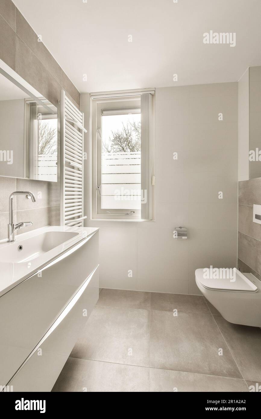 a bathroom with a toilet, sink, and window in the back wall to the ...