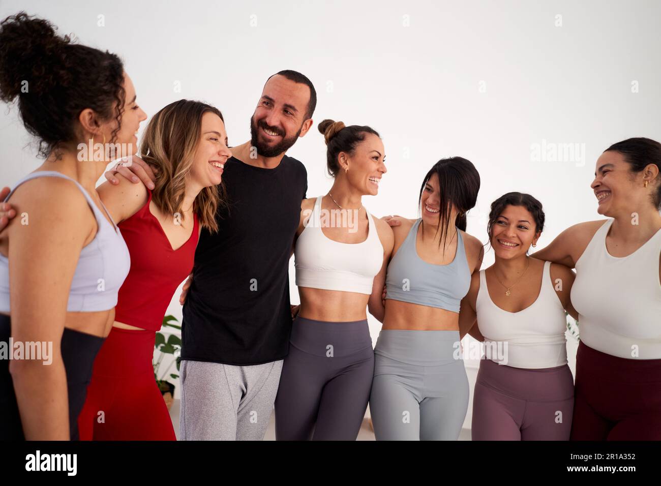 Group of yoga class colleagues embracing each other standing front of ...
