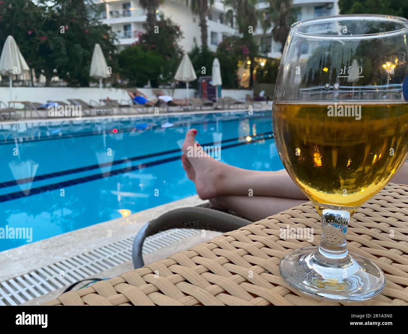 Glass goblet of cold fresh delicious ice cold beer in front of the pool ...