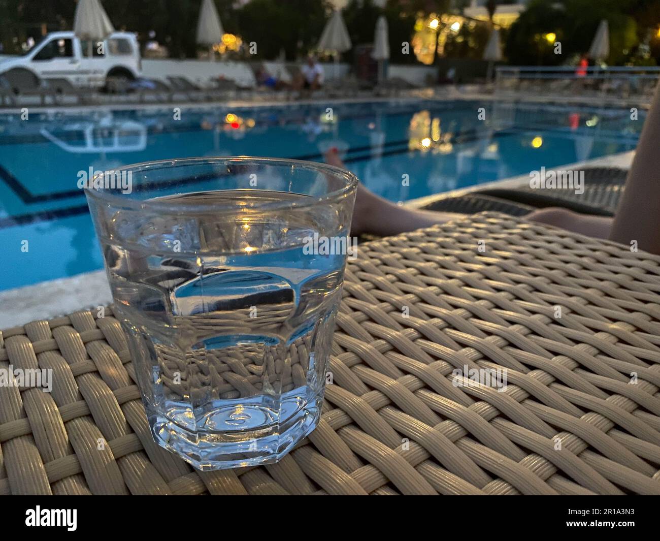 A glass with a clear alcoholic delicious drink in front of the pool in ...