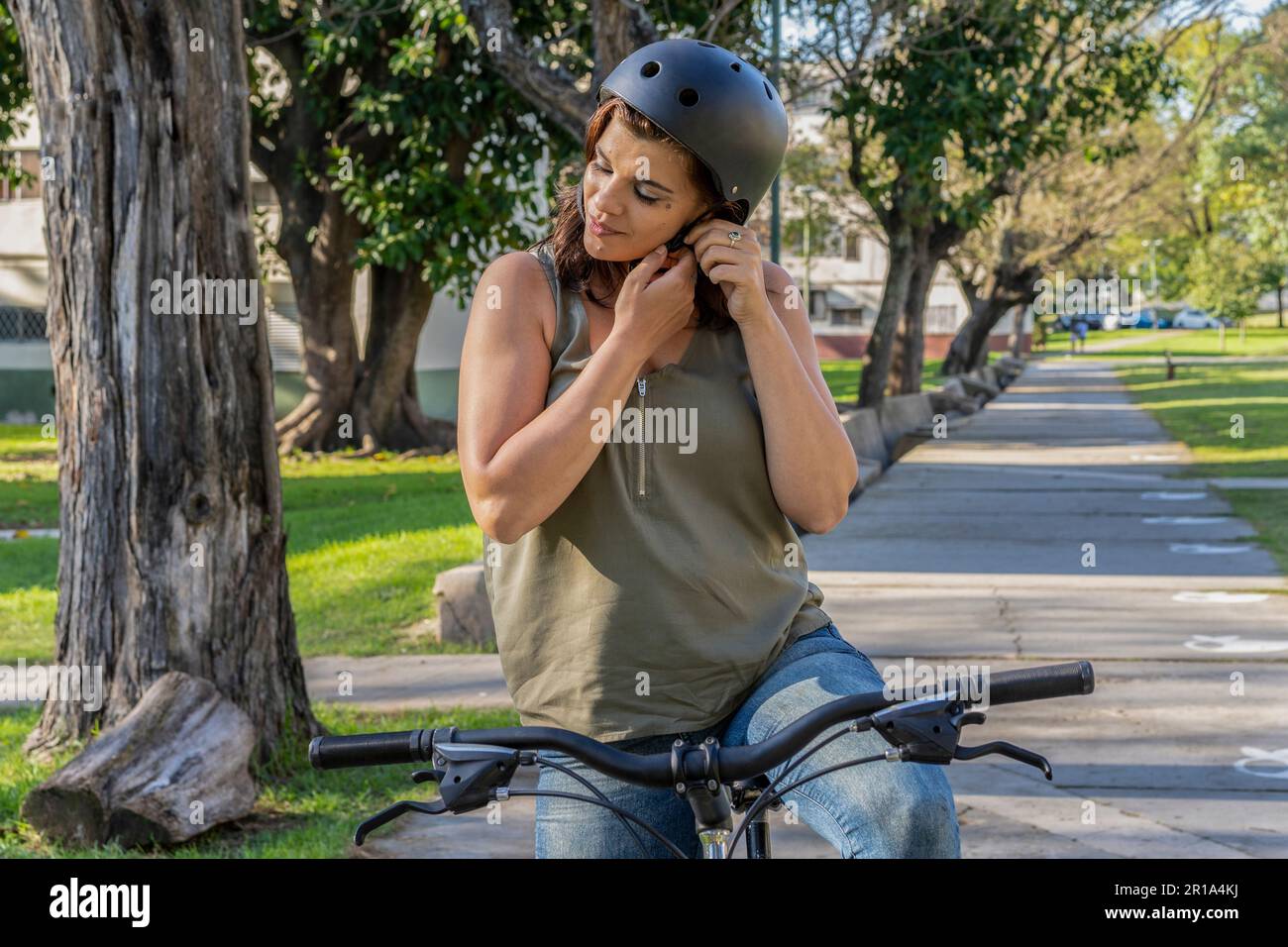Portrait of a young woman on her bike putting on a black helmet Stock Photo - Alamy
