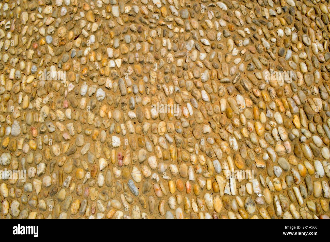 Texture of a stone wall, roads from small round and oval stones with ...