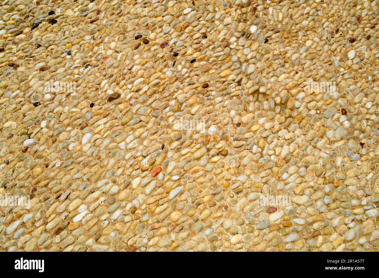 Texture of a stone wall, roads from small round and oval stones with ...