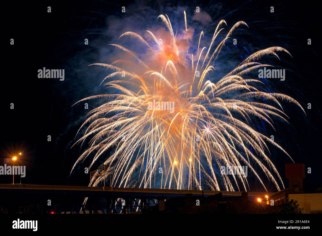A fireworks burst illuminates the sky above a highway bridge in ...