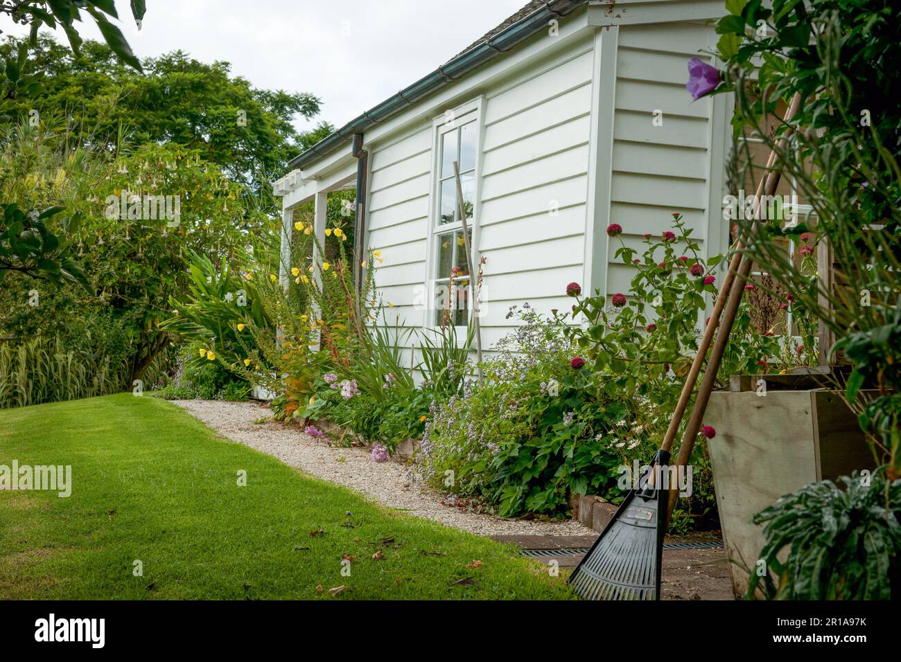Old English style garden with rakes leaning on planter and lawn around ...