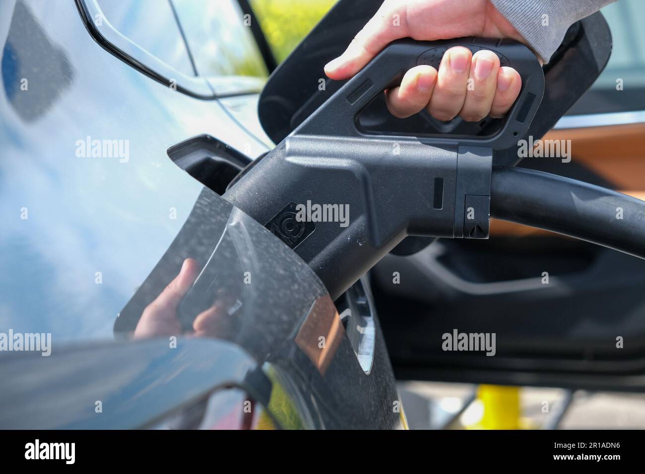 Someone holding electric car charger with hand near plugin socket ...
