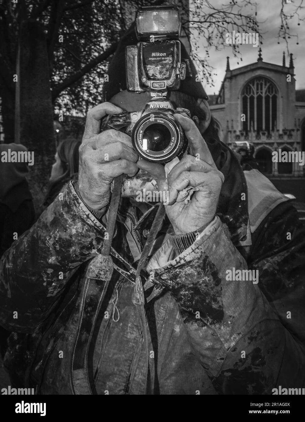 A black and white image of a photographer covered in paint at a ...