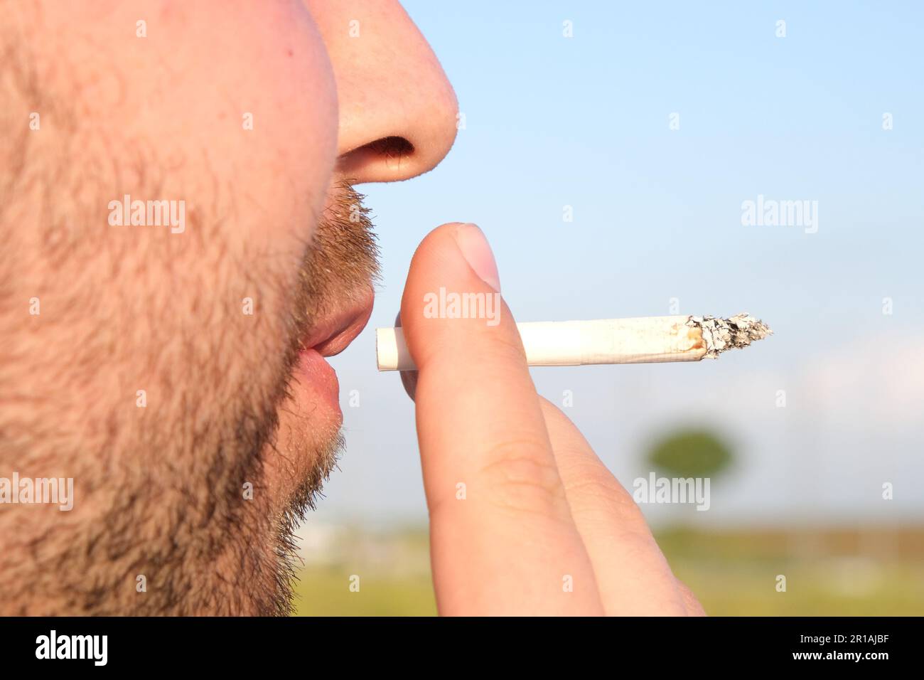 Close-up of man face holding cigarette and smoking. Cancer health ...