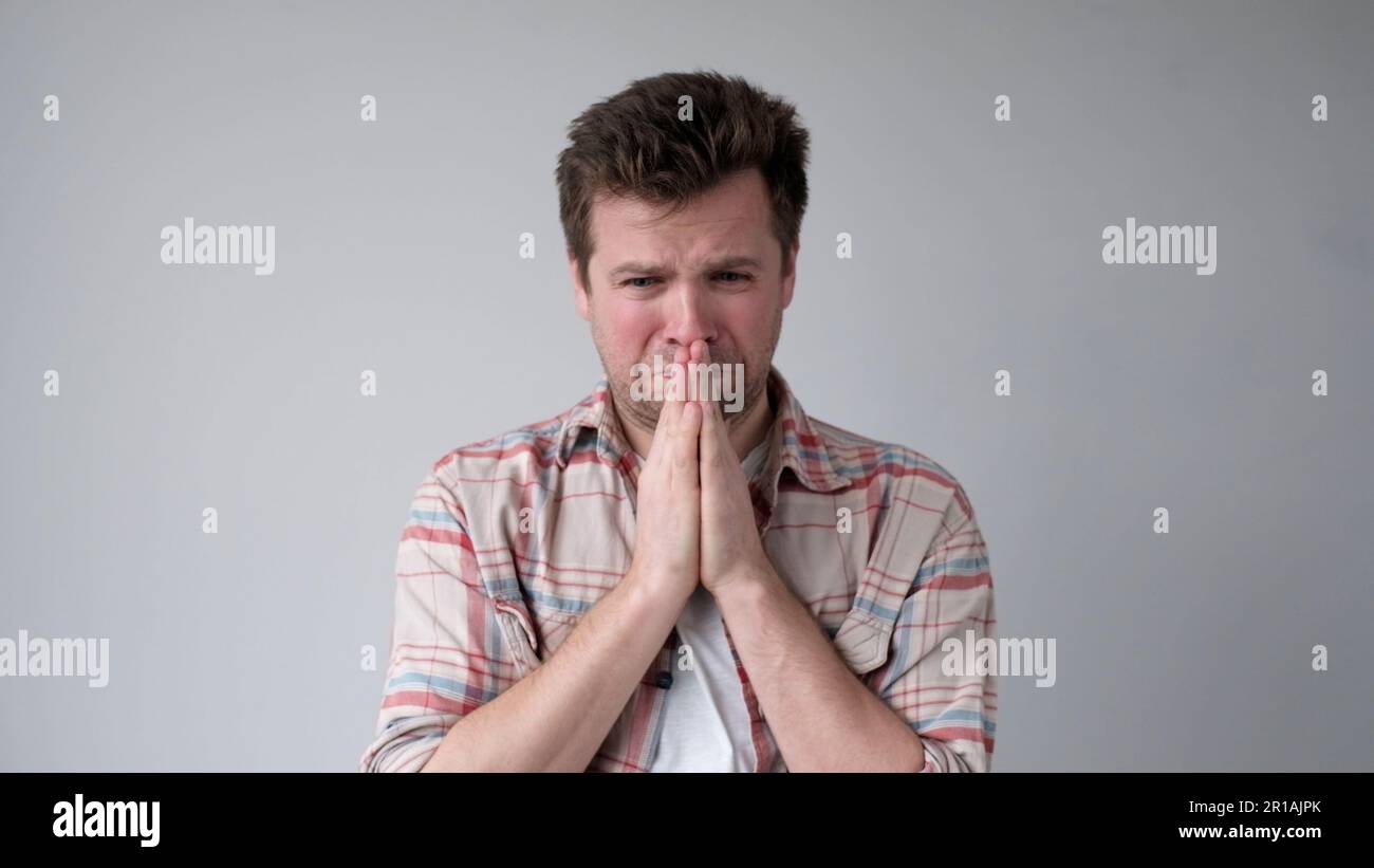 The tired European young man, lacking energy, closes his face with ...