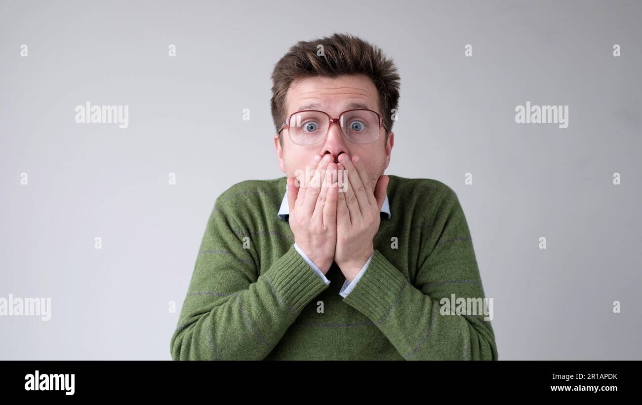 The European young man, in shock, covers his mouth with his hands ...