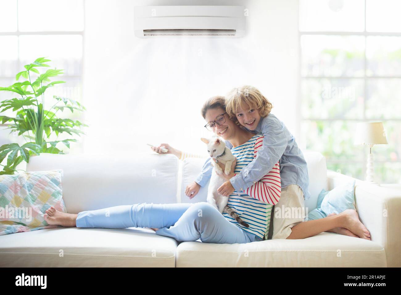 Mother and child with air conditioner remote control. Comfortable ...
