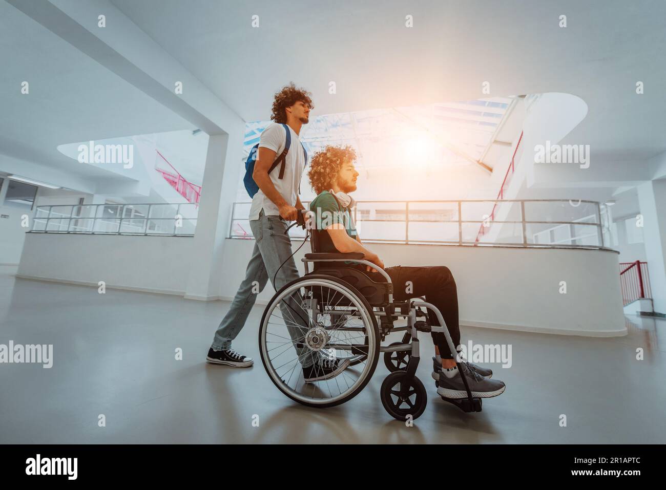 African American student pushing his friend's wheelchair through a ...