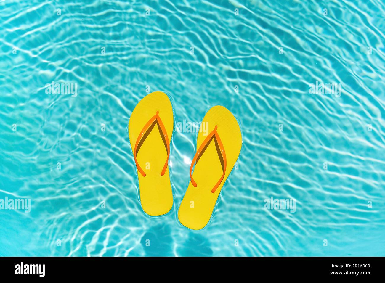 Yellow Flip Flops floating in the water of a clear blue swimming pool ...