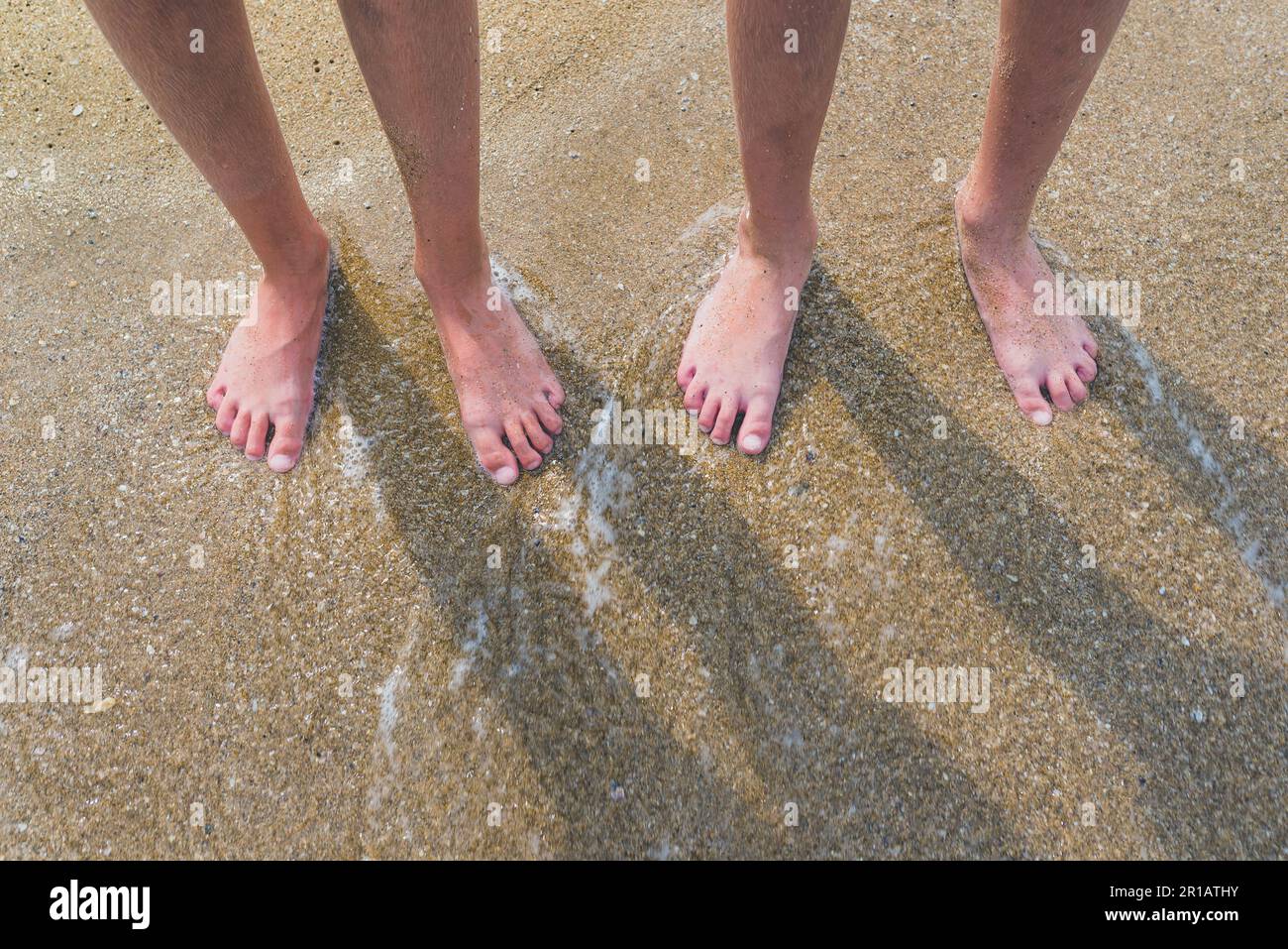 Two pairs of kids feet on the sand in the water .Family on vacations ...