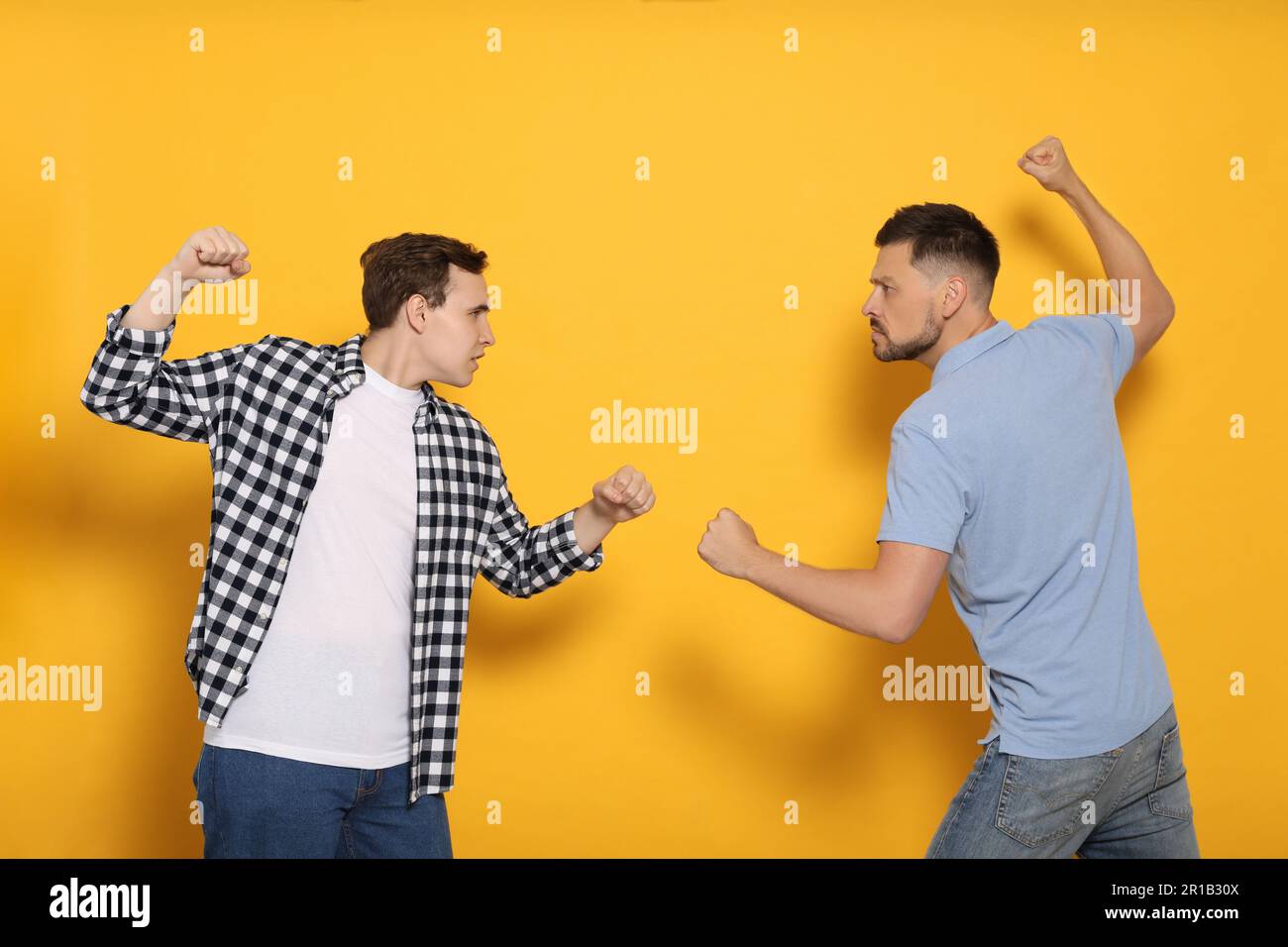 Two emotional men fighting on yellow background Stock Photo - Alamy