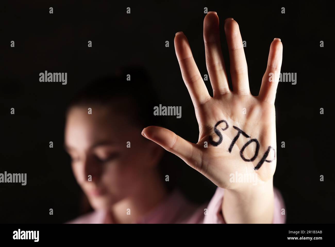 Woman with word Stop written on hand against dark background, closeup ...