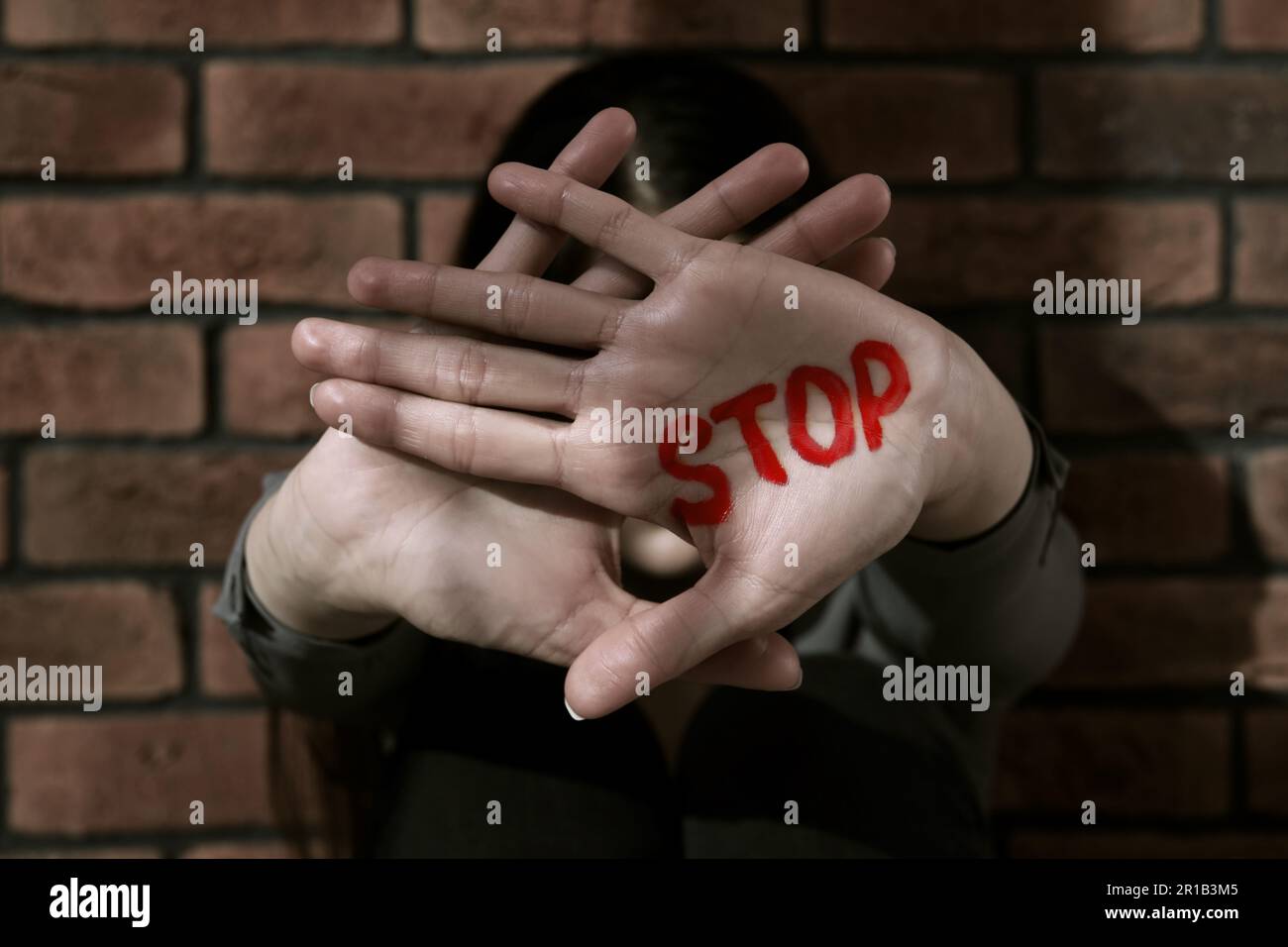 Domestic violence concept. Woman hiding her face, focus on hands with written word Stop Stock ...
