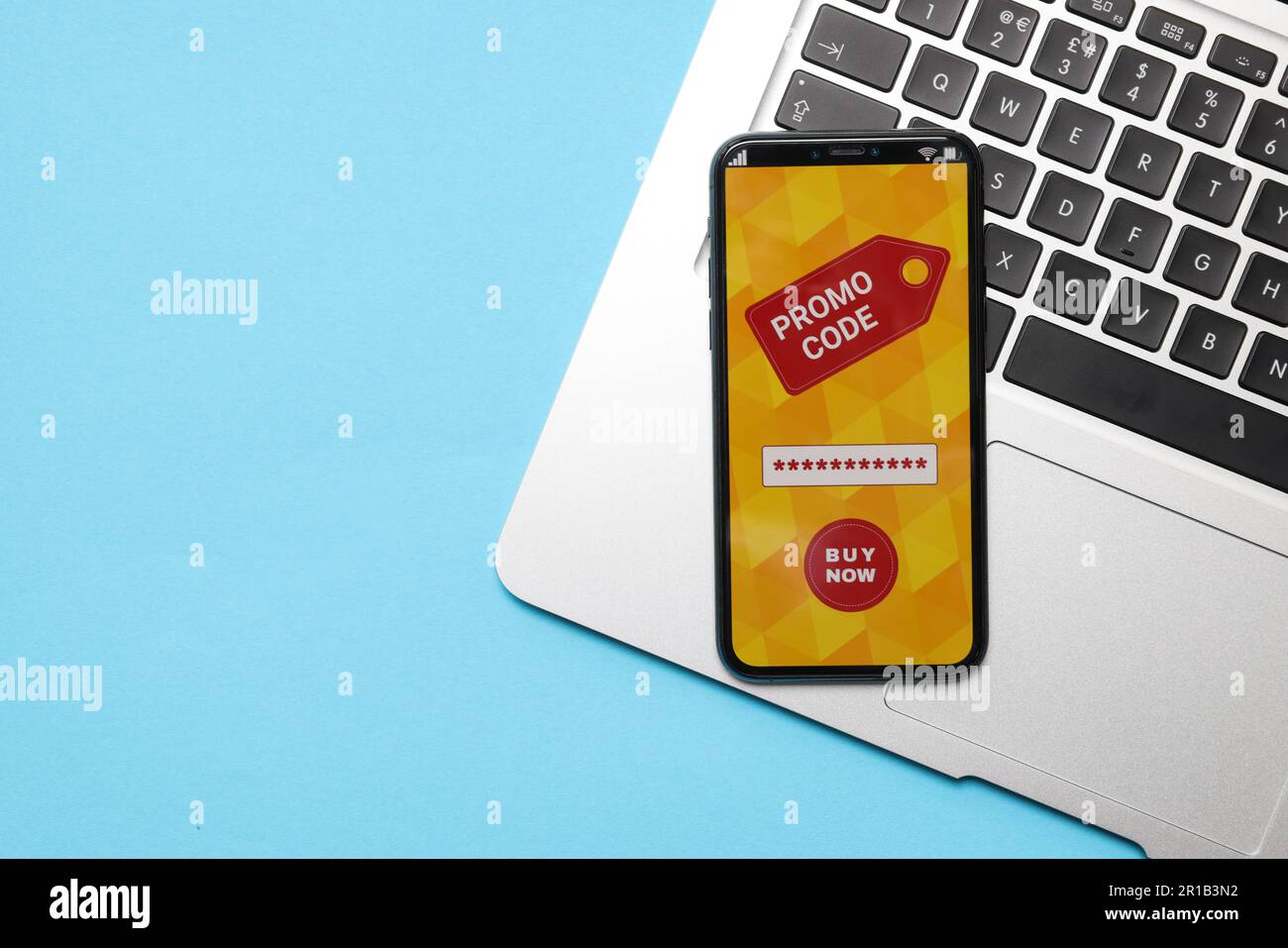 Smartphone with activated promo code and laptop on light blue ...