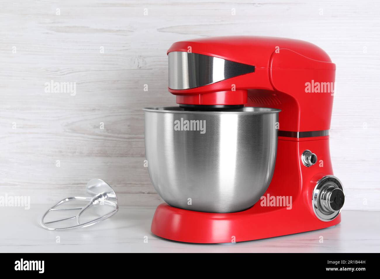 Modern red stand mixer and flat beater on white marble table, space for ...