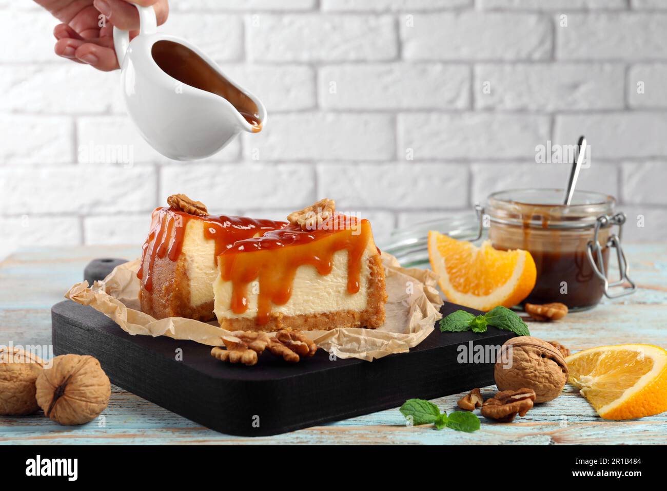 Woman pouring caramel sauce onto delicious pieces of cheesecake at ...
