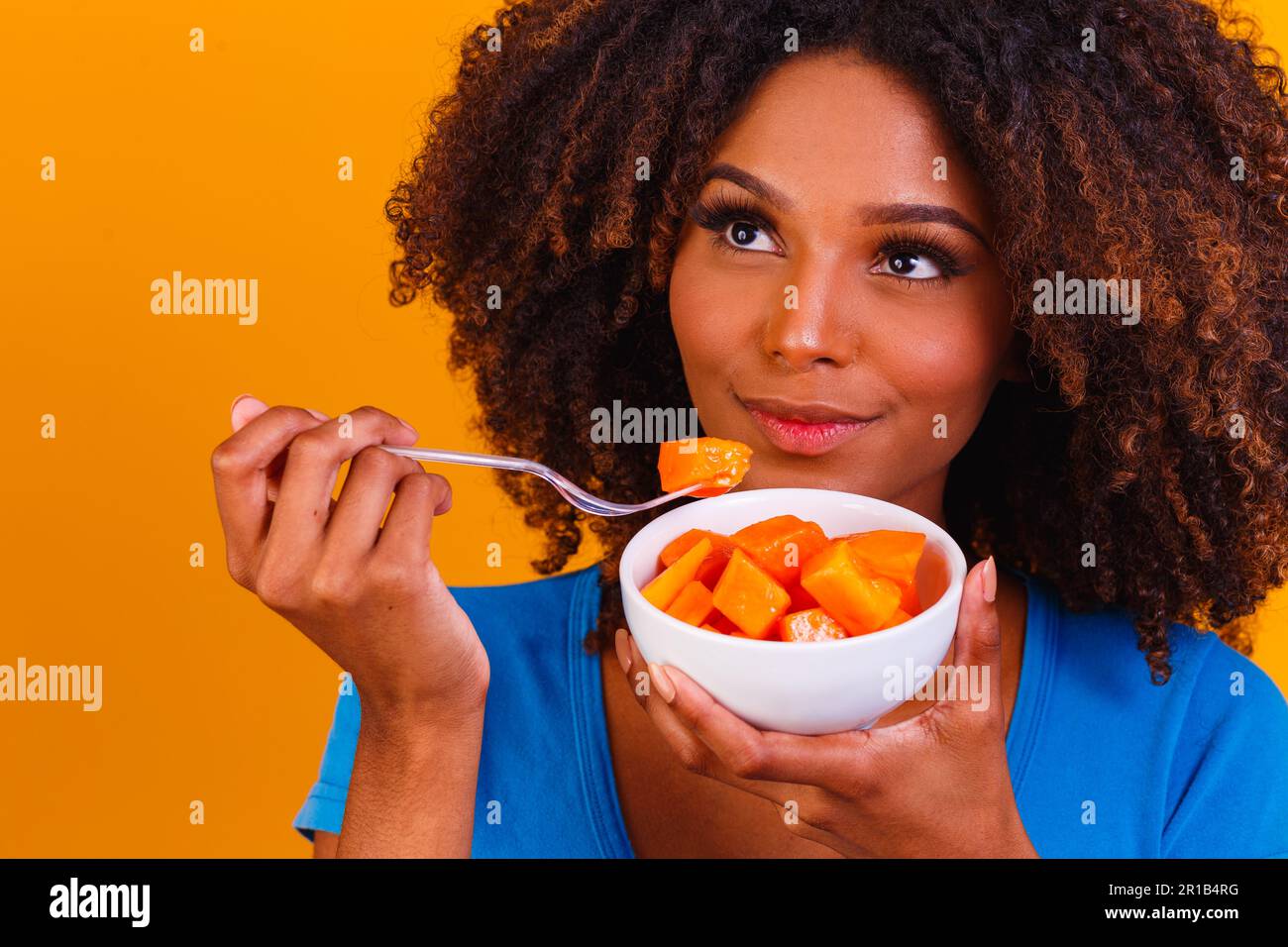 afro girl eating papaya from the bowl. Healthy eating concept Stock ...